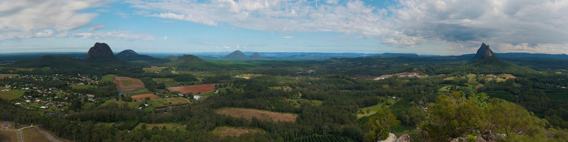 Paisagem montanhosa com uma aldeia, colinas ondulantes e céu claro.
