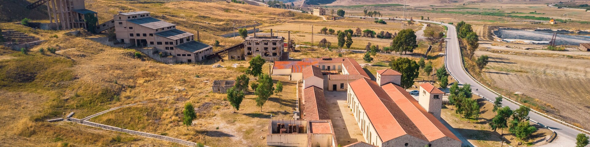 Um complexo industrial abandonado, com vários edifícios e uma estrada sinuosa.