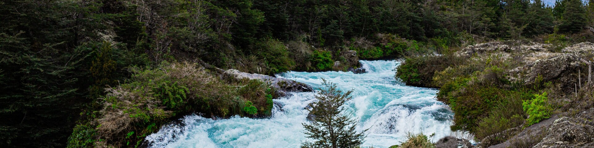 Uma cachoeira imponente cercada por floresta densa e montanhas ao fundo.