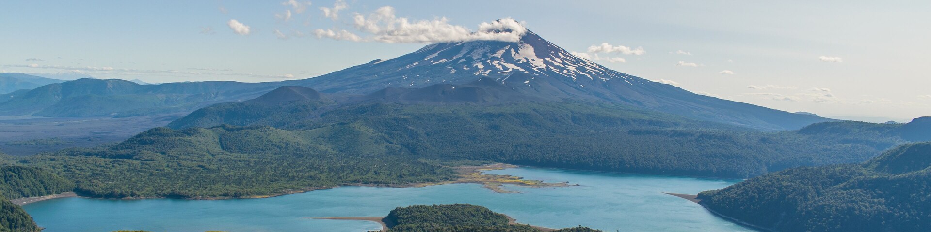 Montanha com um lago na base e um vale arborizado.