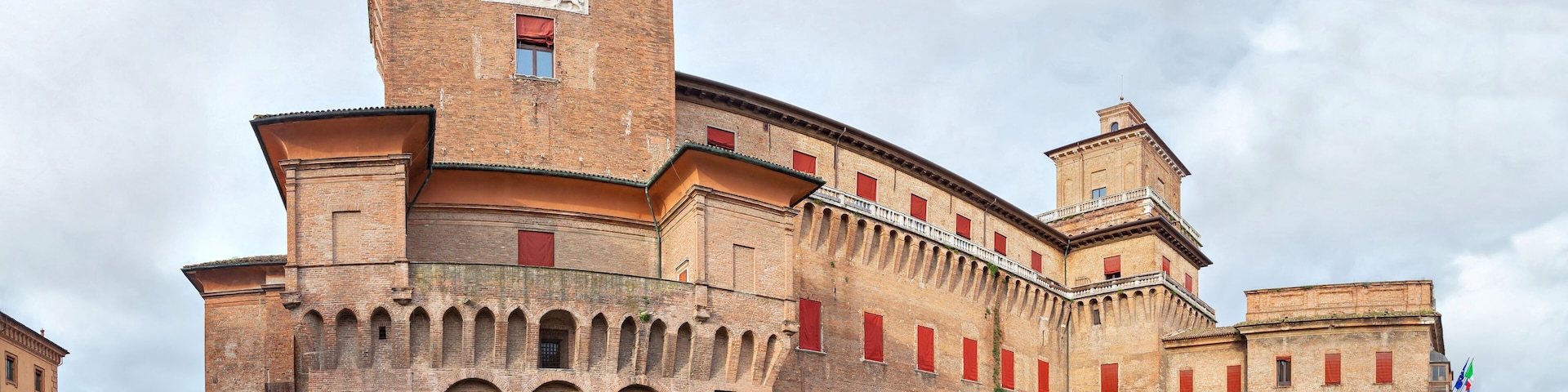 Um edifício histórico de tijolos com janelas em arco e uma torre.