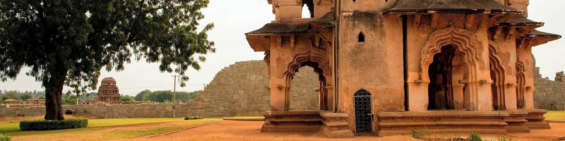 Um templo antigo com esculturas detalhadas e uma grande árvore em primeiro plano.