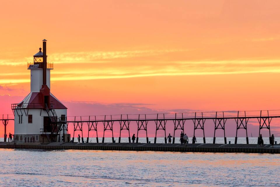 Um farol e um cais ao pôr do sol.
