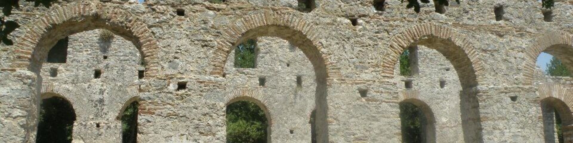 Estrutura antiga de pedra com várias aberturas em arco e uma placa indicando importância histórica.