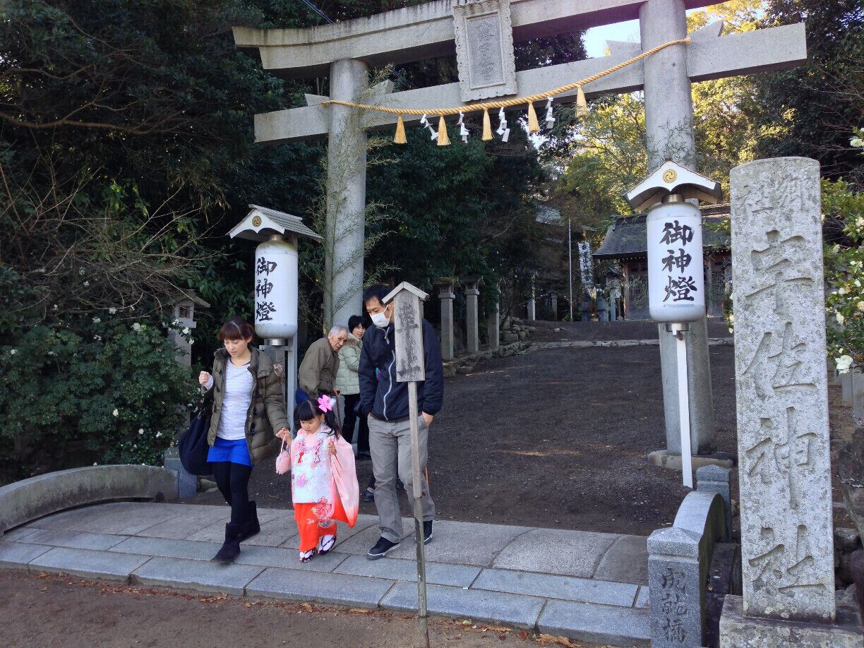 Um grupo de pessoas caminhando perto de uma estrutura de pedra com inscrições japonesas.
