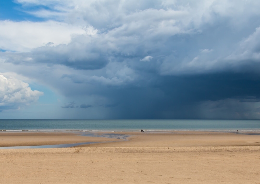 Uma praia com céu tempestuoso e um arco-íris.