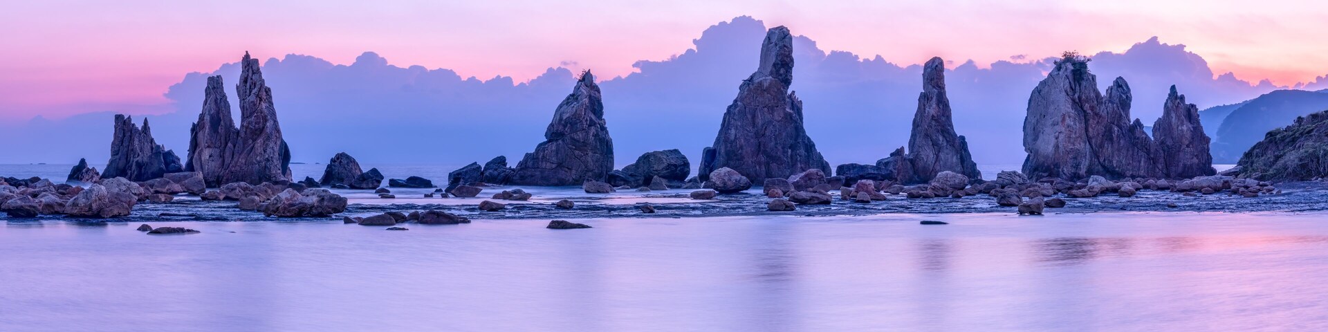 Paisagem costeira com formações rochosas imponentes e mar calmo.
