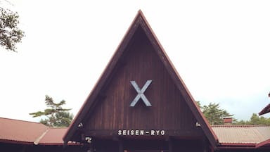 Um edifício de madeira com telhado triangular e um grande 'X' na fachada.