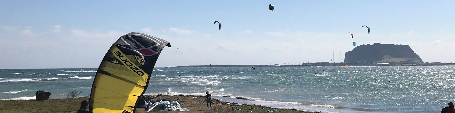 Uma praia com equipamentos de windsurf e kites.