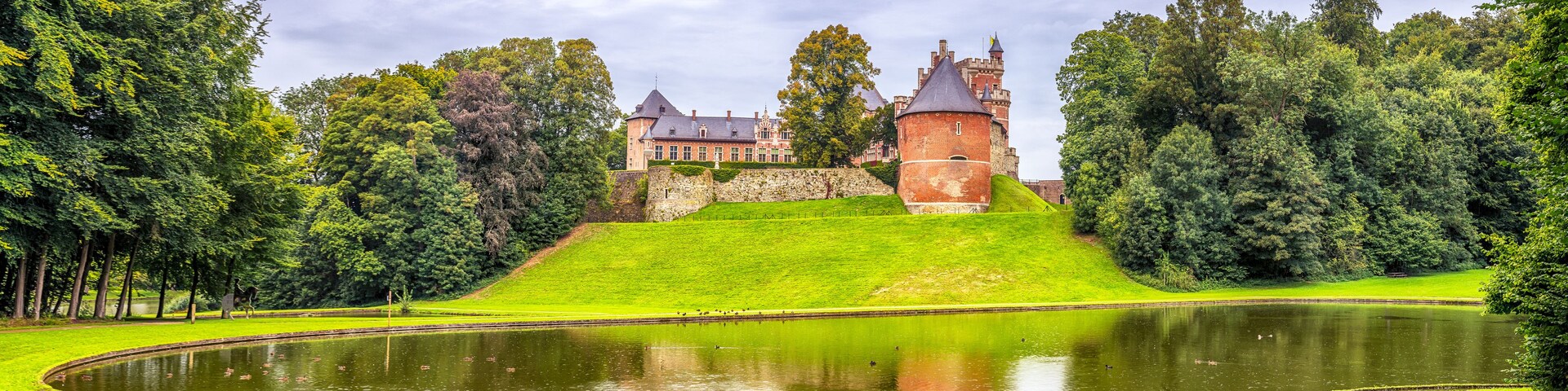 Um castelo rodeado por um fosso e vegetação exuberante.