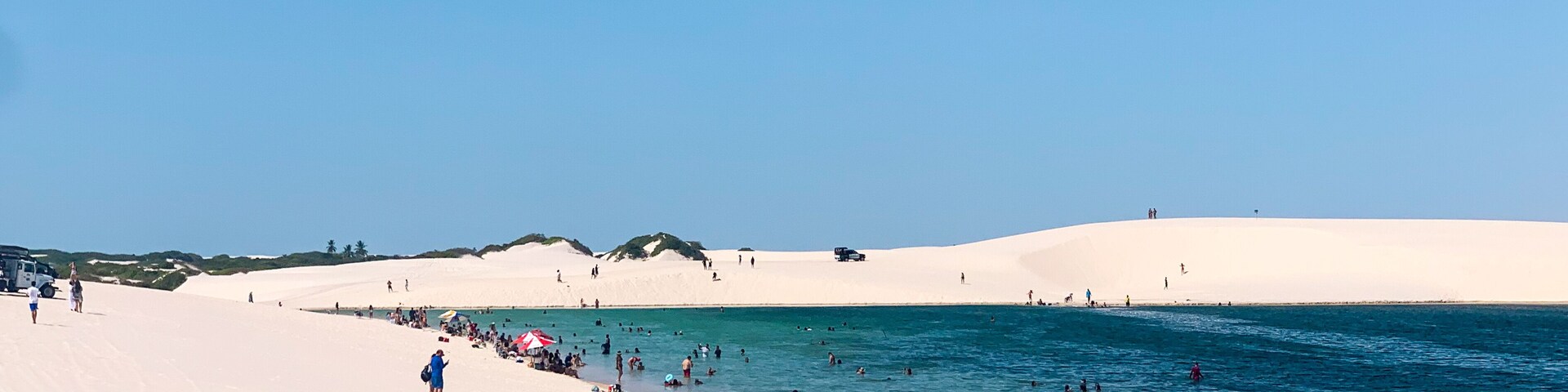 Uma praia com dunas de areia branca e águas azul-claras.