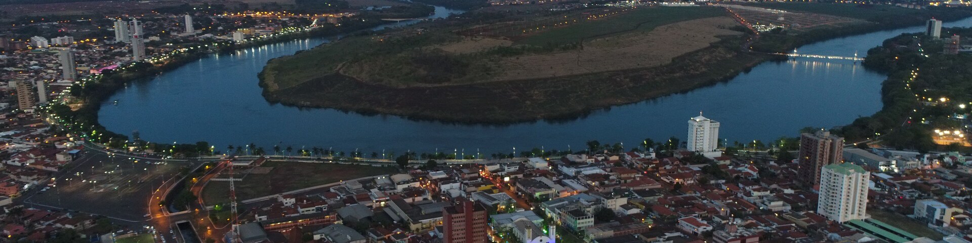 Um rio serpenteando por uma cidade com edifícios e uma ponte.