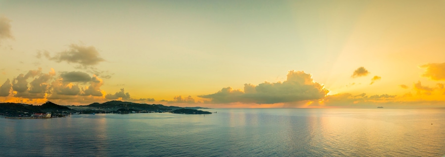 Mar calma ao pôr do sol, com uma pequena ilha e um navio ao longe.