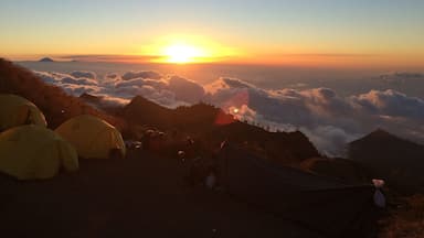 Nascer do sol sobre uma cordilheira, com barracas montadas ao lado.