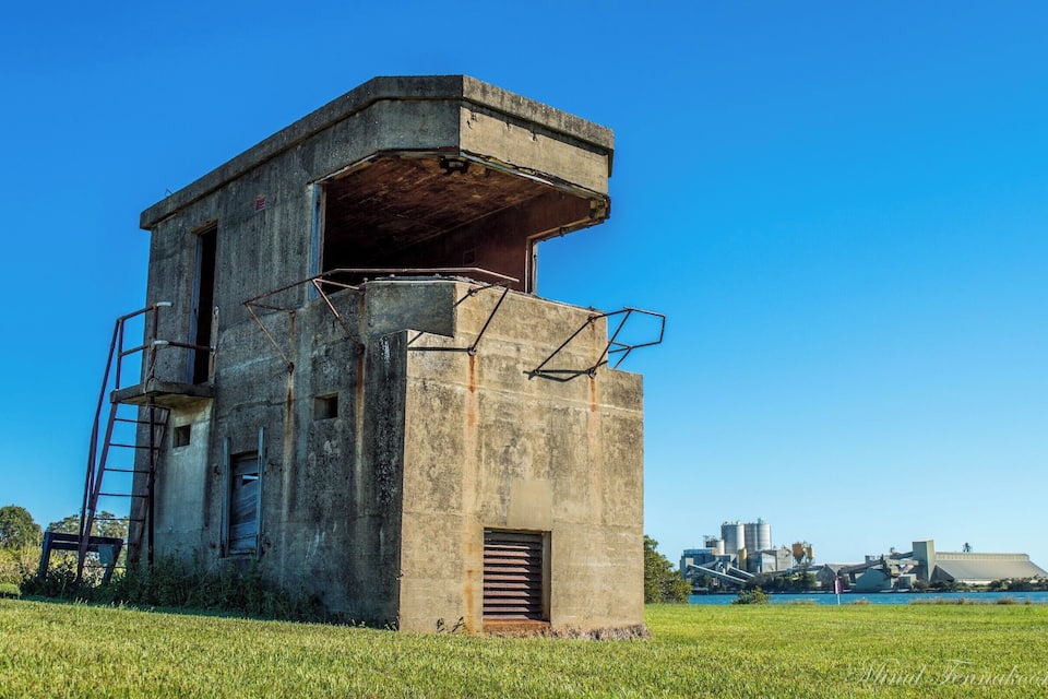 Uma estrutura de concreto abandonada com uma escada, um portão de metal e uma pequena janela.