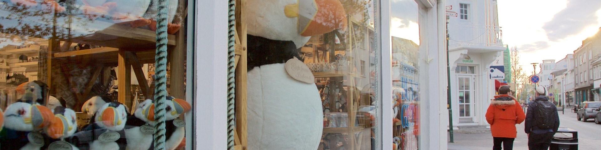 Vitrine de loja com pinguins de pelúcia e uma grande figura de boneco de neve.