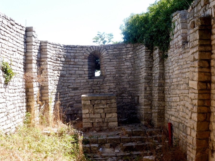 Uma construção antiga de pedra com uma janela central em arco e uma pequena plataforma.