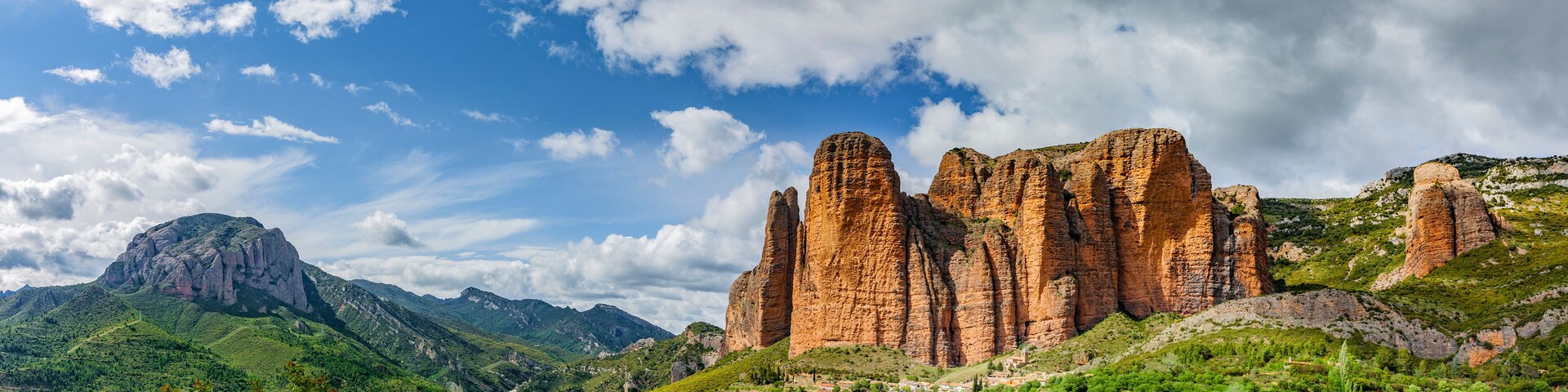 Paisagem montanhosa com uma rocha imponente e uma aldeia.