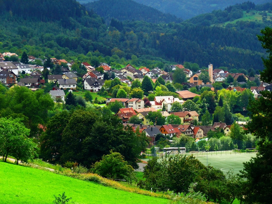 Uma vila aninhada num vale, com casas, uma igreja e um campo de futebol.