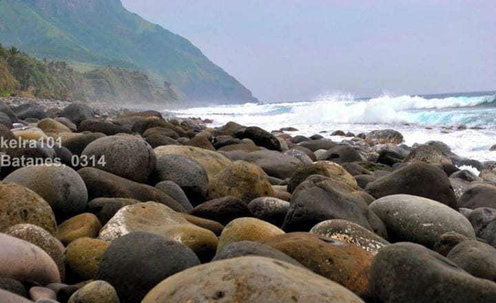Uma praia rochosa com ondas quebrando na costa.