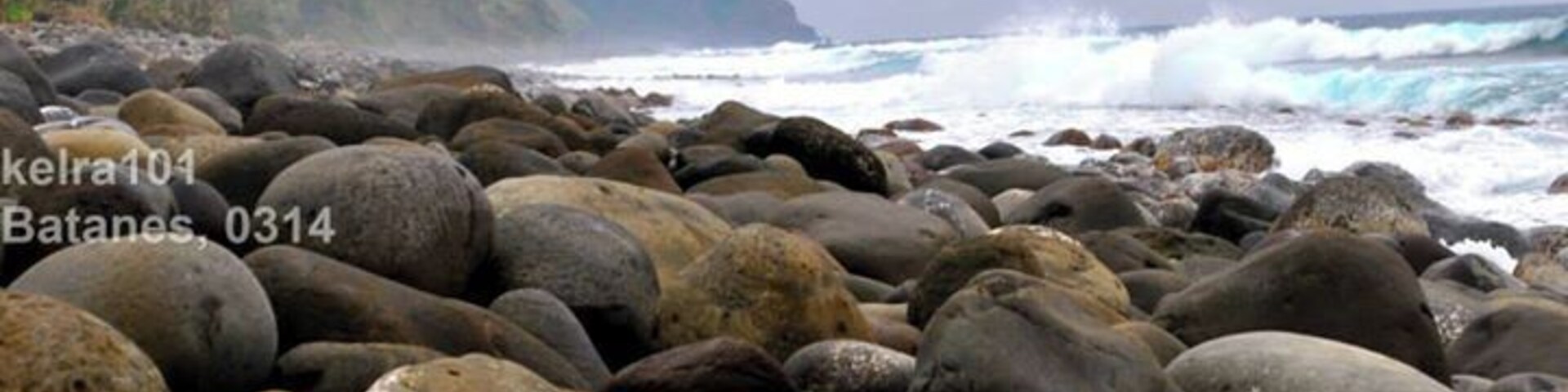 Uma praia rochosa com ondas quebrando na costa.