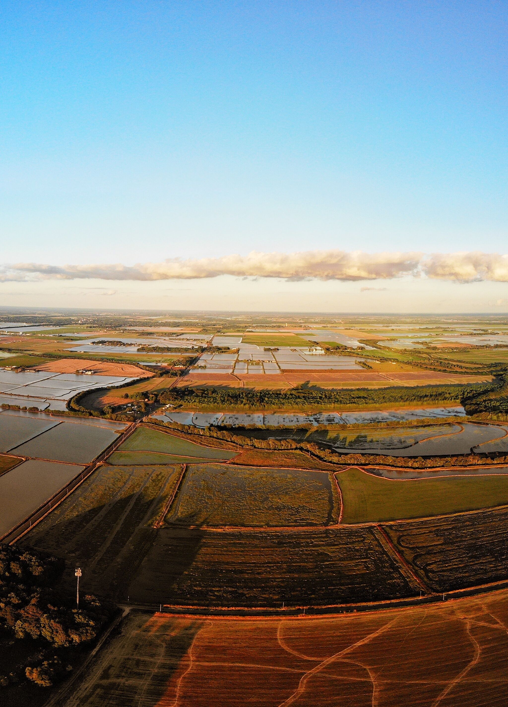 Vista aérea de uma extensa paisagem agrícola com diversos campos e corpos d'água.