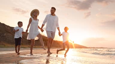 Uma família caminhando na praia durante o pôr do sol.