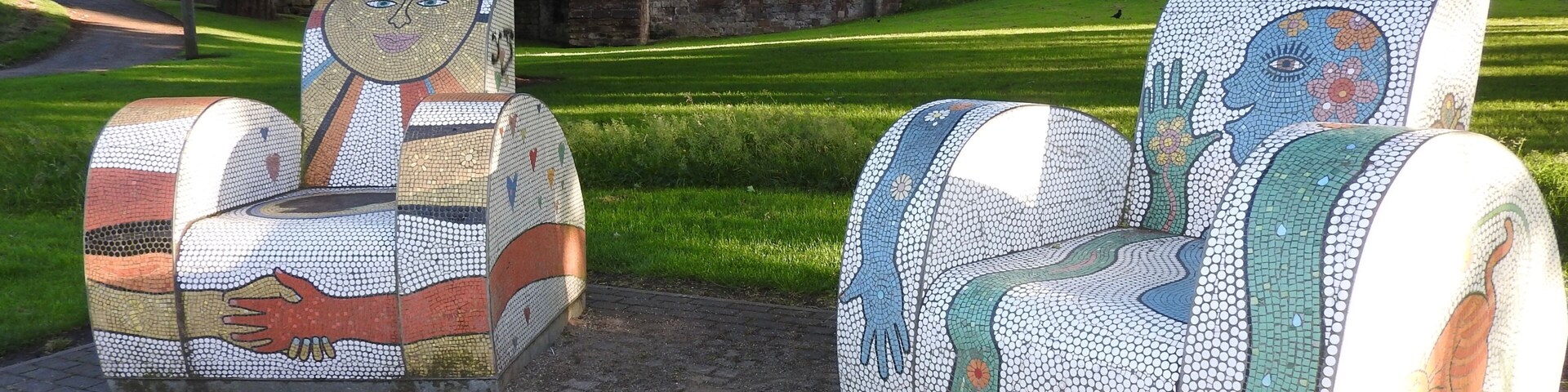 Duas poltronas de mosaico em um parque.