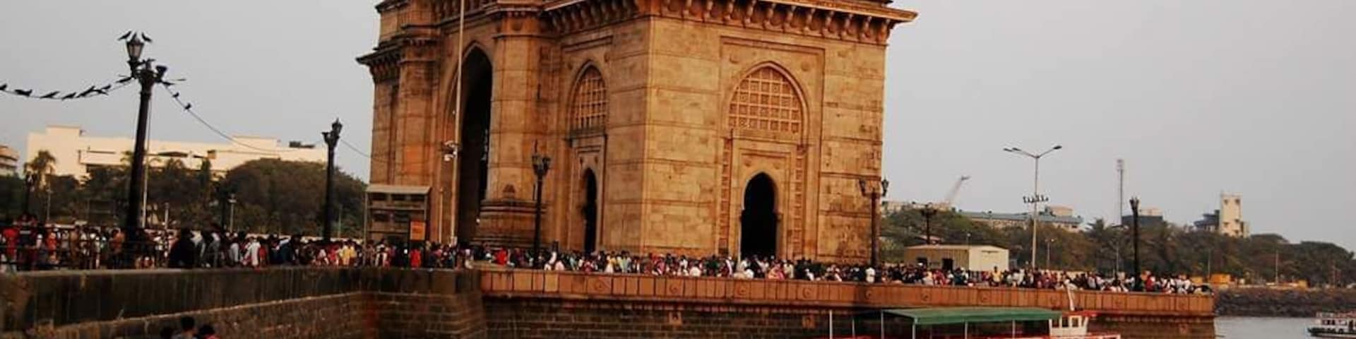 O Portão da Índia em Mumbai, Índia, com barcos e pessoas ao redor da estrutura.