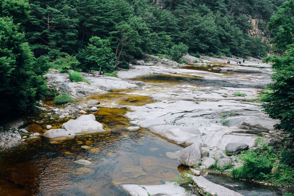 Um rio serpenteando por uma paisagem rochosa com vegetação verde exuberante.
