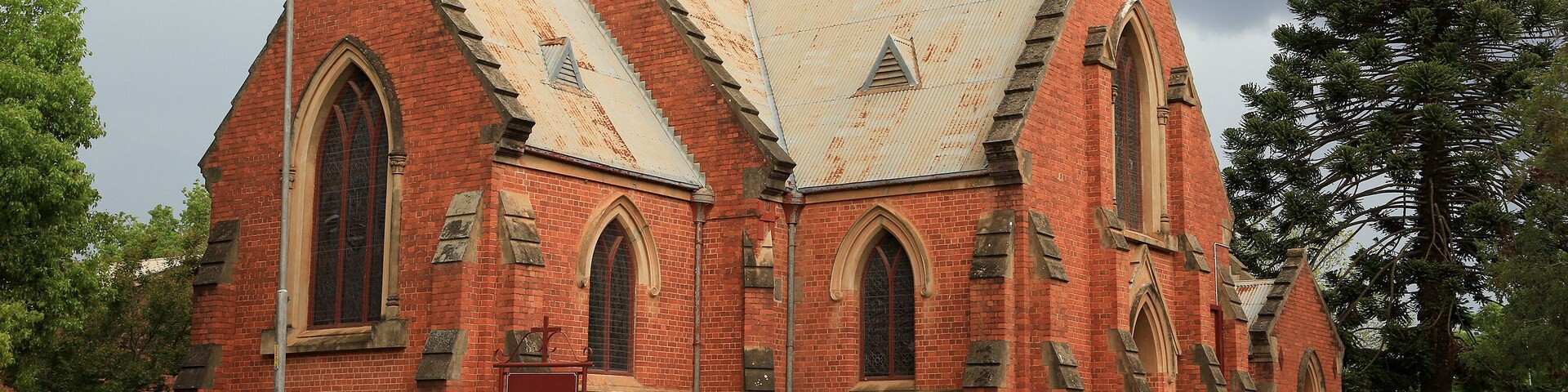 Uma igreja de tijolos vermelhos, com arcos ogivais e telhado íngreme.