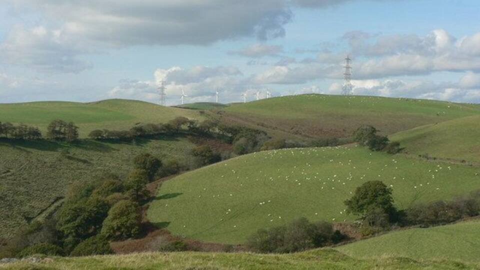 Valley between Mynedd Meiros and Mynedd Portref Wind turbines can be seen on the ridge above the pastures of the valley.
