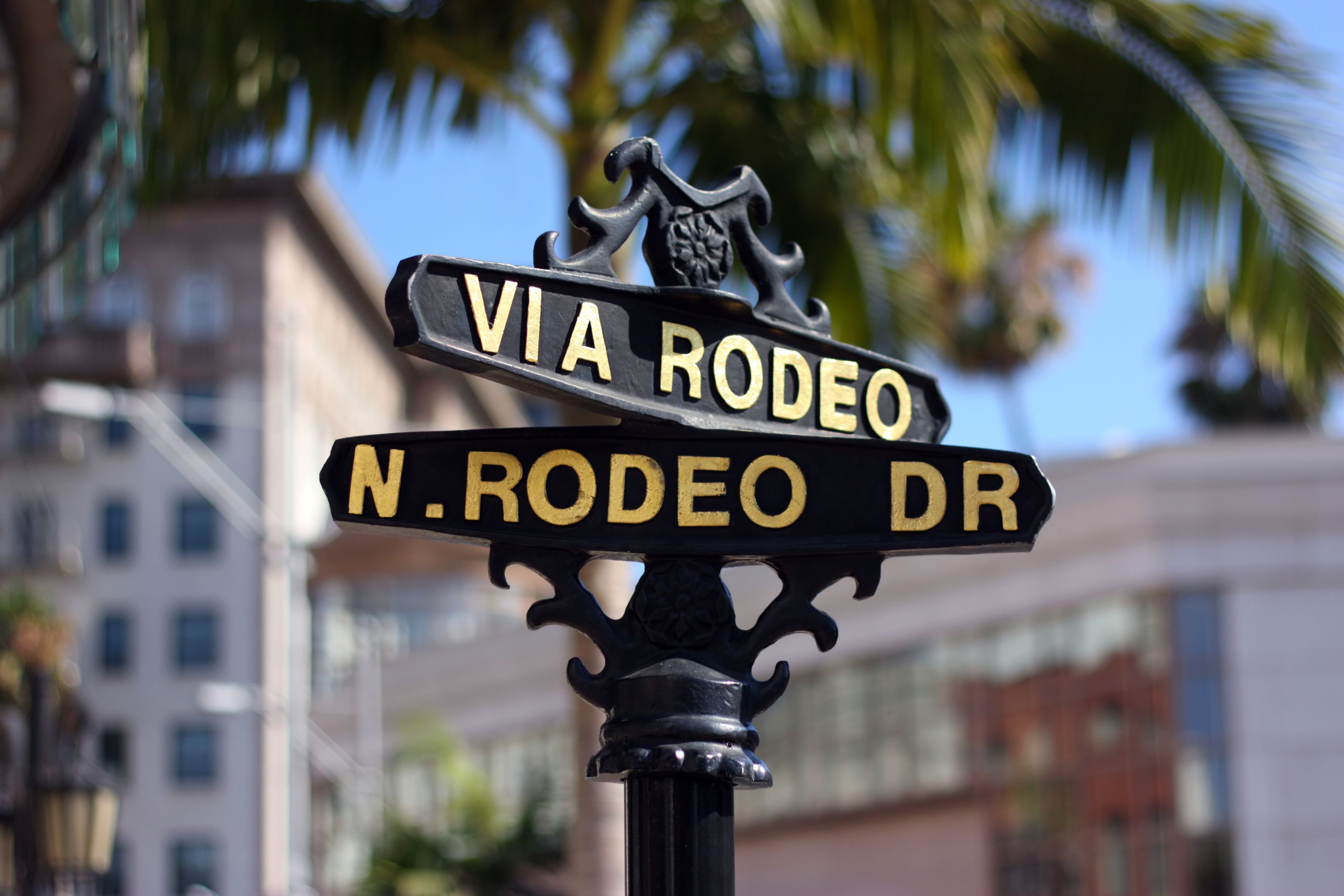 Uma placa de rua com a inscrição 'VIA RODEO' e 'N. RODEO DR'.