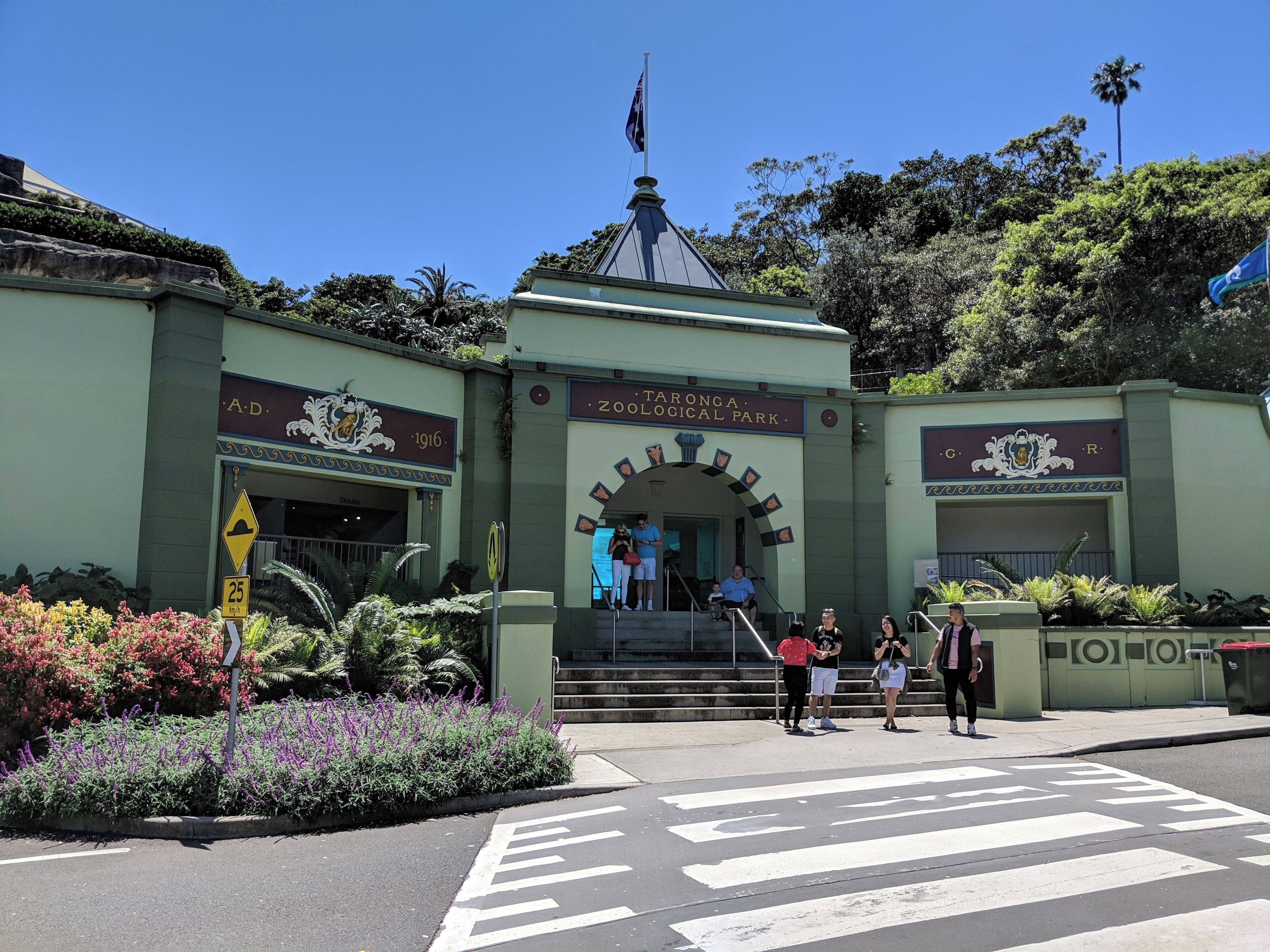 Entrada do Zoológico de Taronga, com uma arcada imponente e vegetação exuberante.