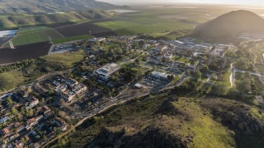 Vista aérea de uma cidade com áreas residenciais, estradas e colinas ao redor.