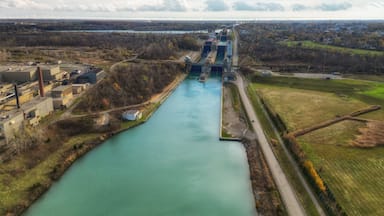 Uma barragem com sistema de eclusas, um rio e áreas industriais e residenciais ao redor.