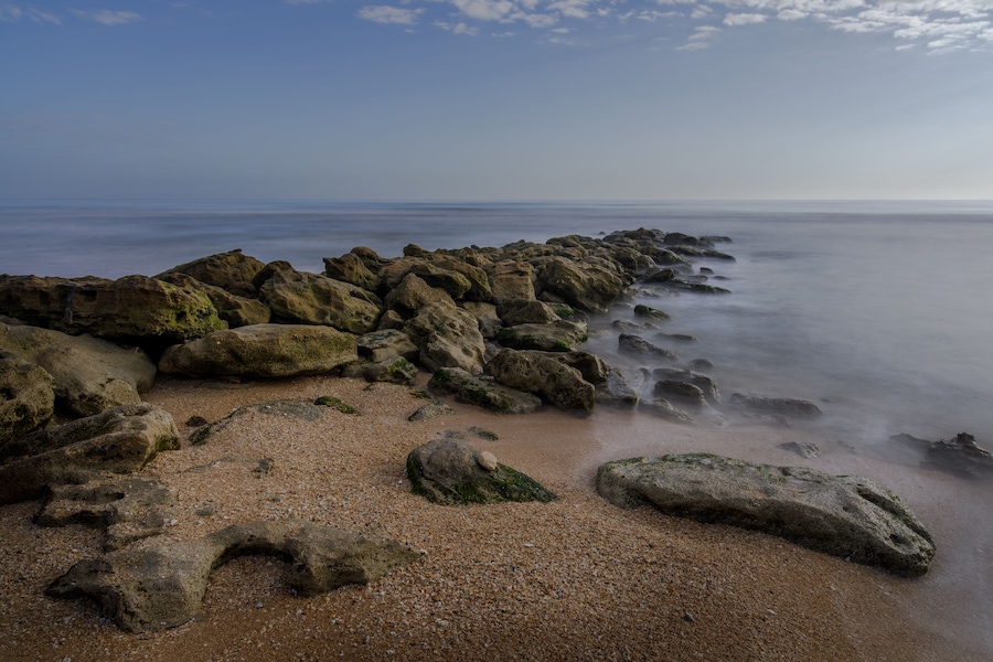 Uma costa rochosa com mar calmo e céu claro.