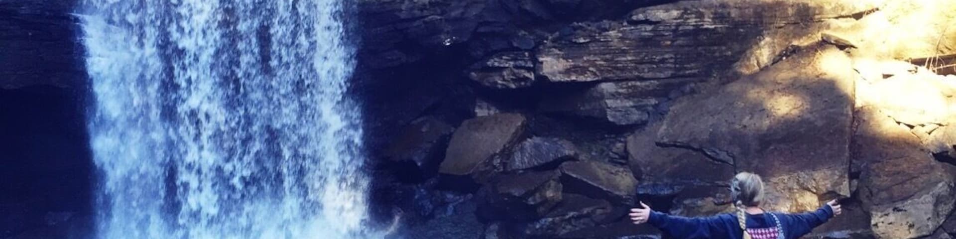 Uma cascata despencando em uma piscina rodeada por penhascos rochosos.