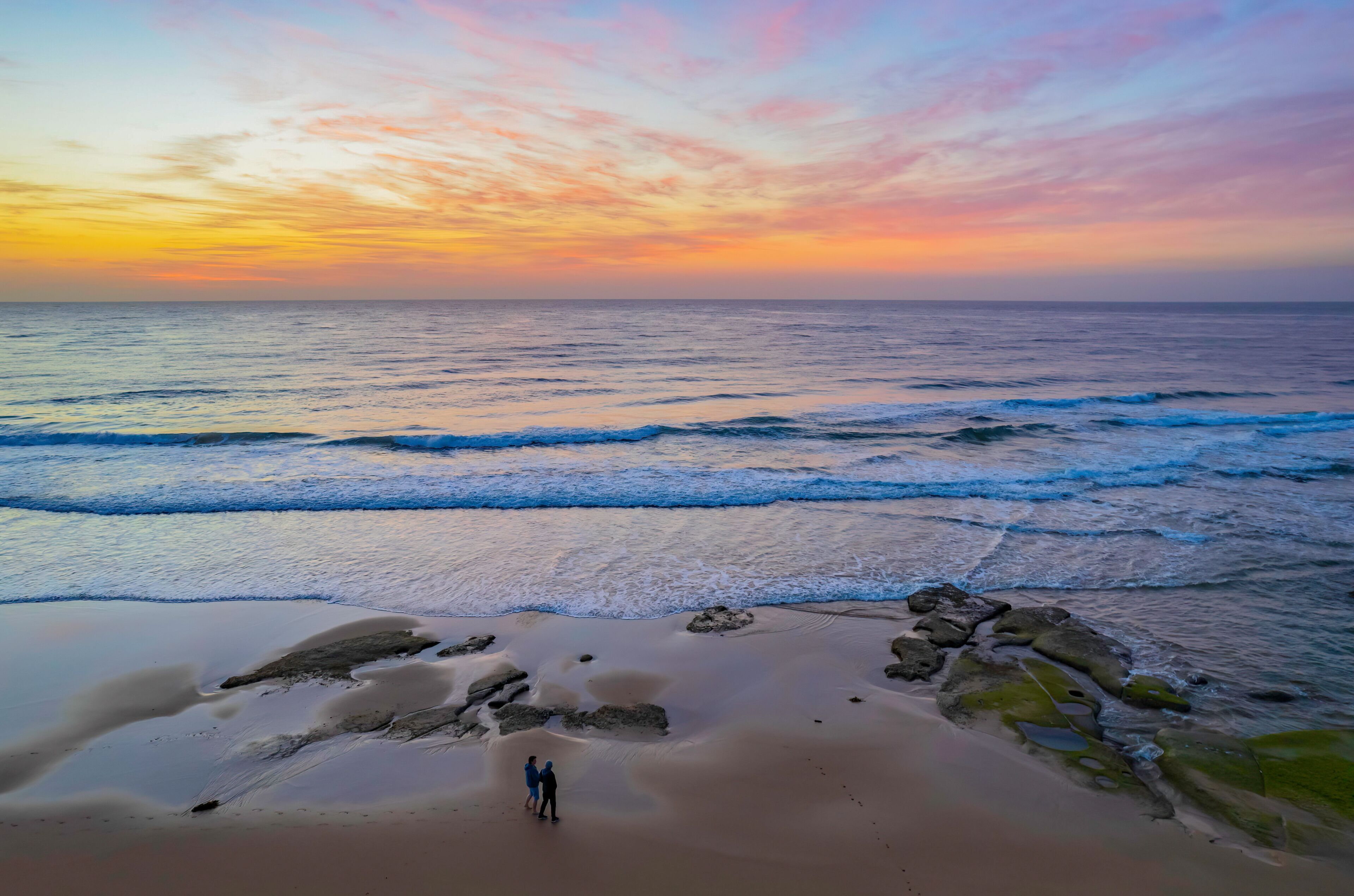 Uma praia com ondas e um céu ao pôr do sol.