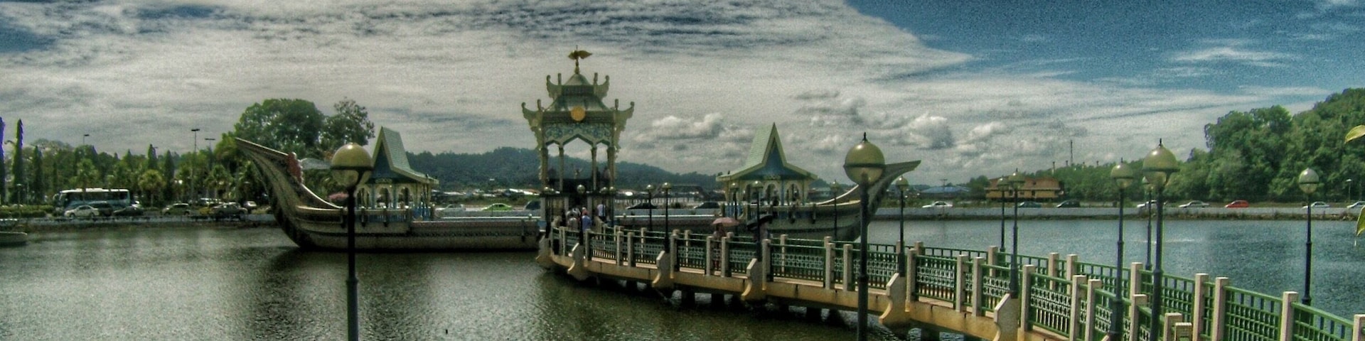 Uma passarela à beira-rio com um coreto e um barco tradicional.