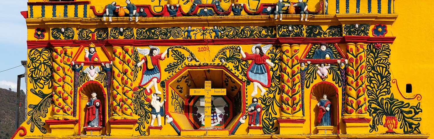 Igreja vibrante com murais detalhados e porta vermelha.