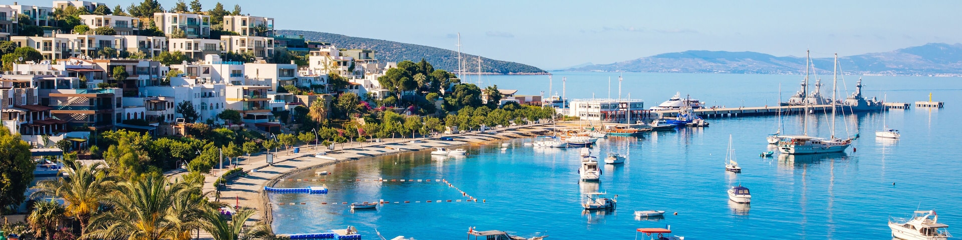 Uma vila costeira com um porto de iates, barcos e edifícios residenciais.
