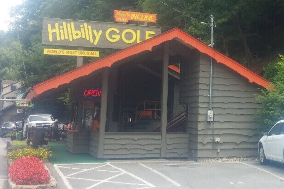 Um pequeno edifício com telhado vermelho e uma placa que diz 'Hillbilly Golf'.