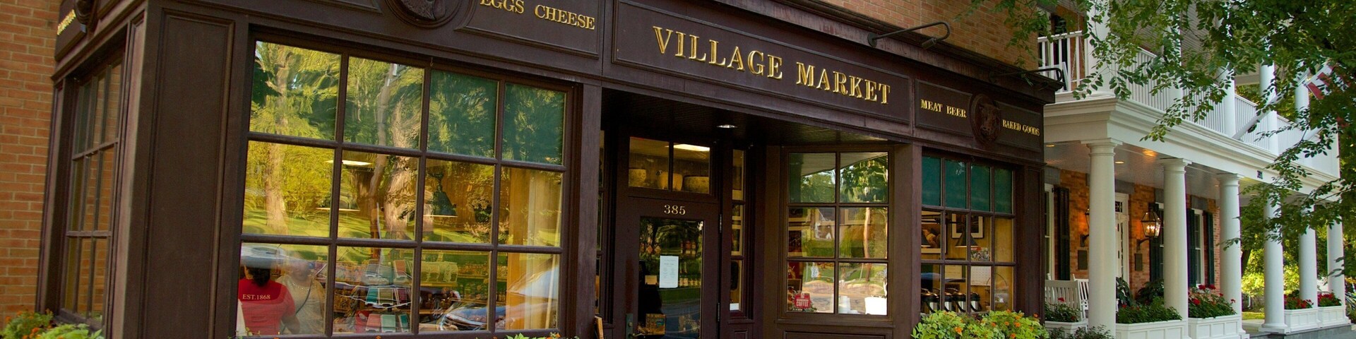 Um edifício de tijolos com grandes janelas e uma placa que diz 'Village Market'.