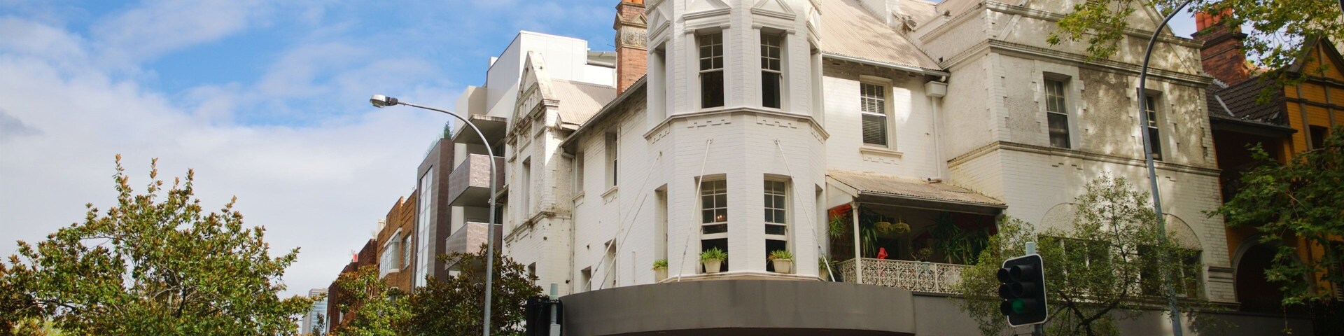 Um edifício histórico com fachada branca, janelas amplas e uma varanda.