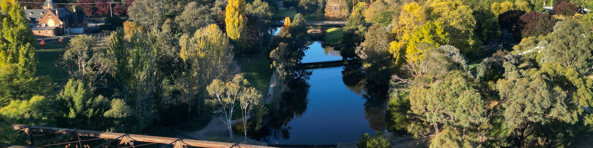 Uma ponte sobre um rio, rodeada por árvores e uma vila ao longe.