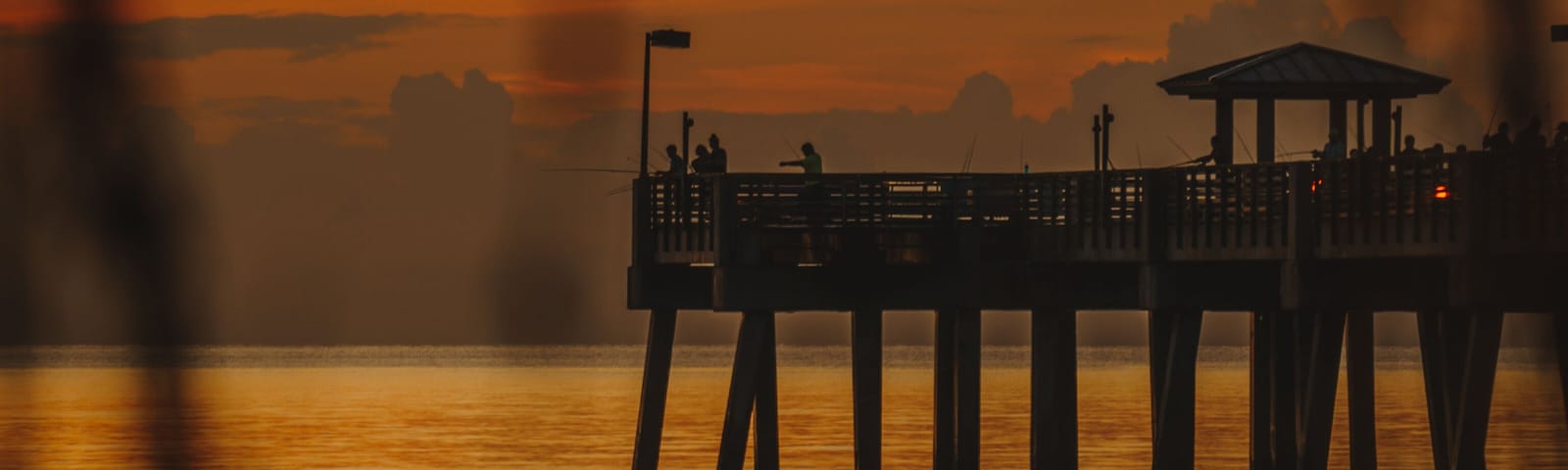Um cais se estendendo sobre a água durante o pôr do sol.