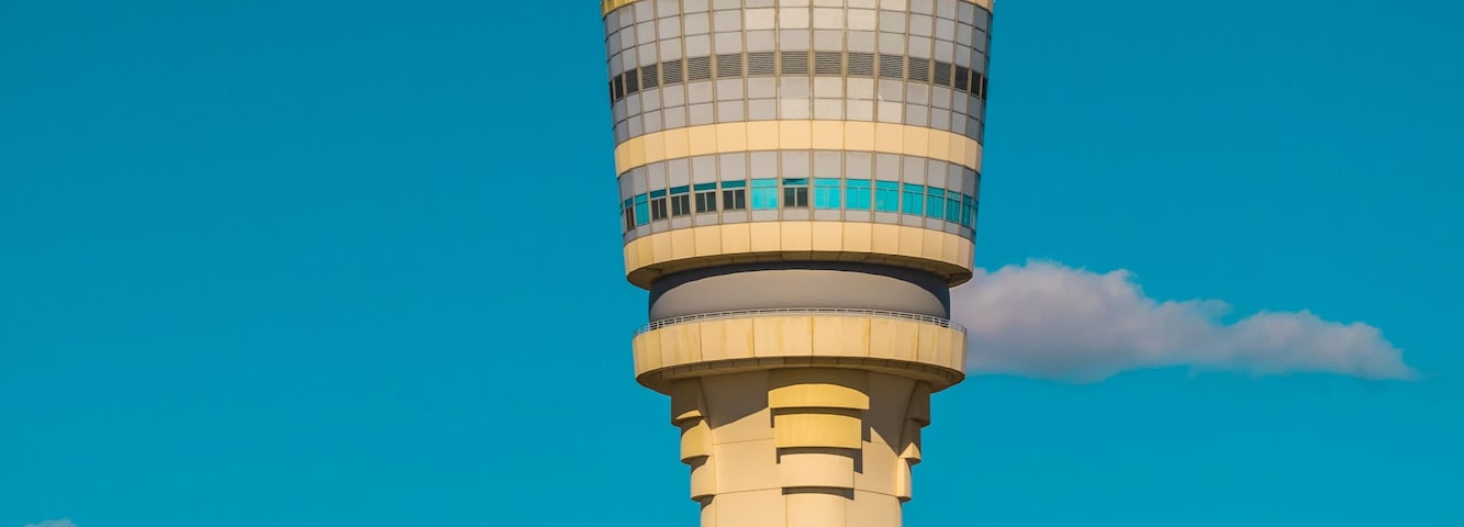 Uma torre de controle com um céu azul límpido ao fundo.