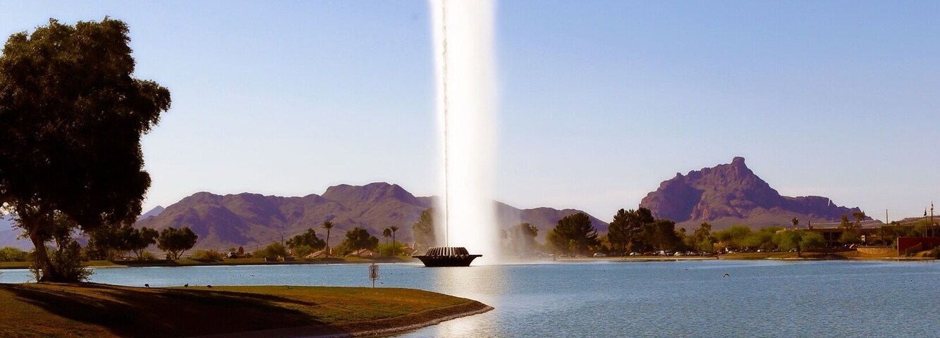 Uma fonte em um lago com montanhas ao fundo.