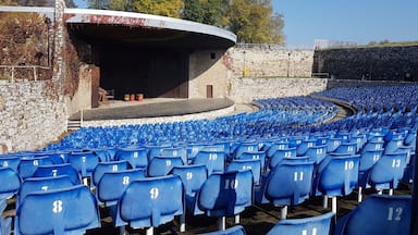 Um anfiteatro ao ar livre com assentos azuis e paredes de pedra.